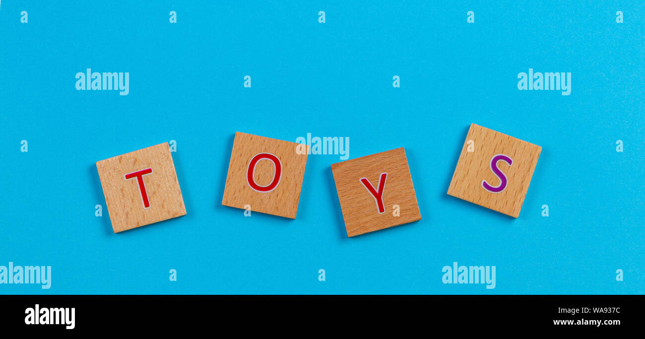 The word TOYS, spelt with wooden letter tiles over blue background. Top ...