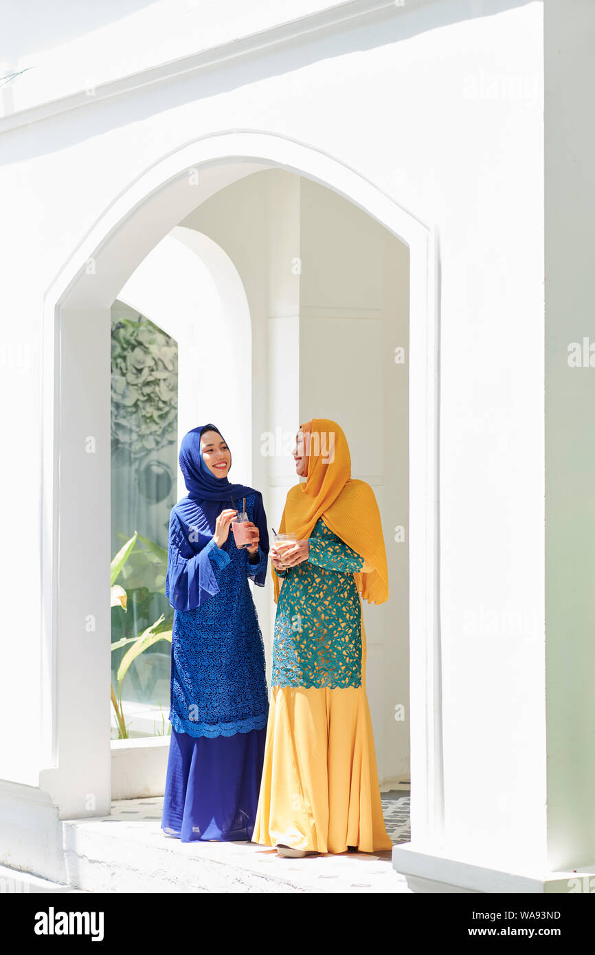 Happy young muslim women standing in house entrance, talking and ...