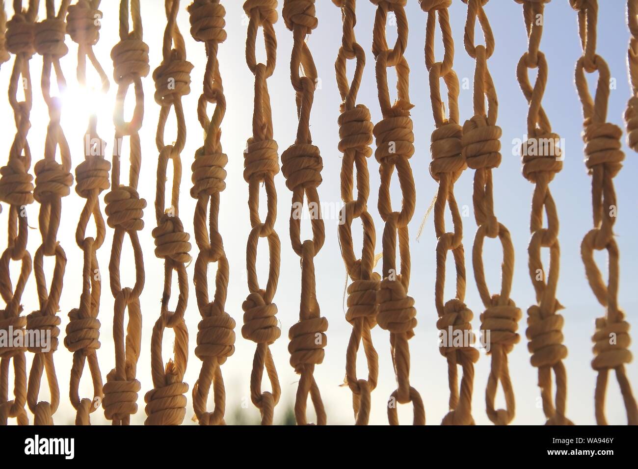 Close shot of rope knotted together with the sun shining through at ...