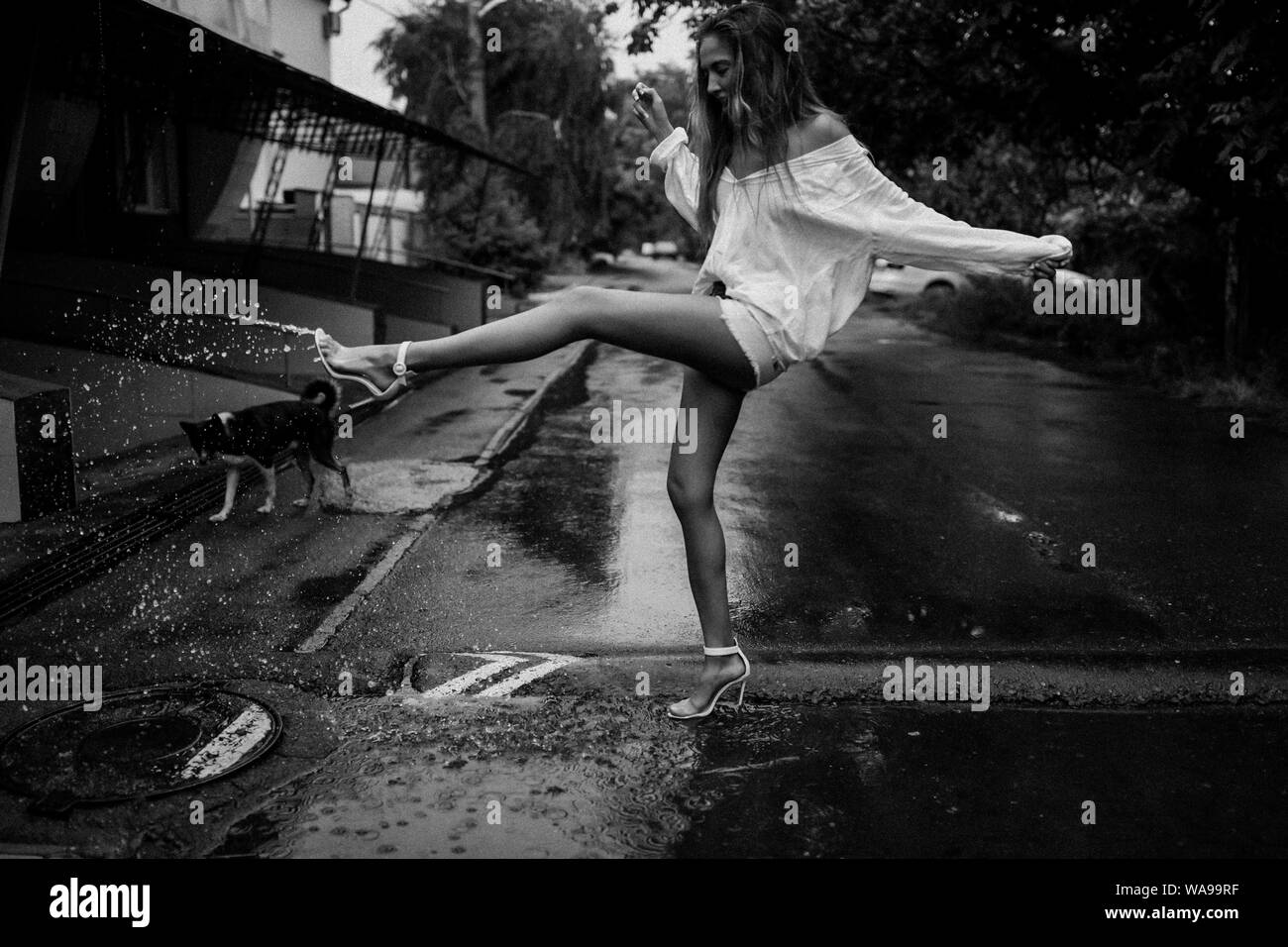 Attractive lady splashing water in a puddle with her tender leg in a ...