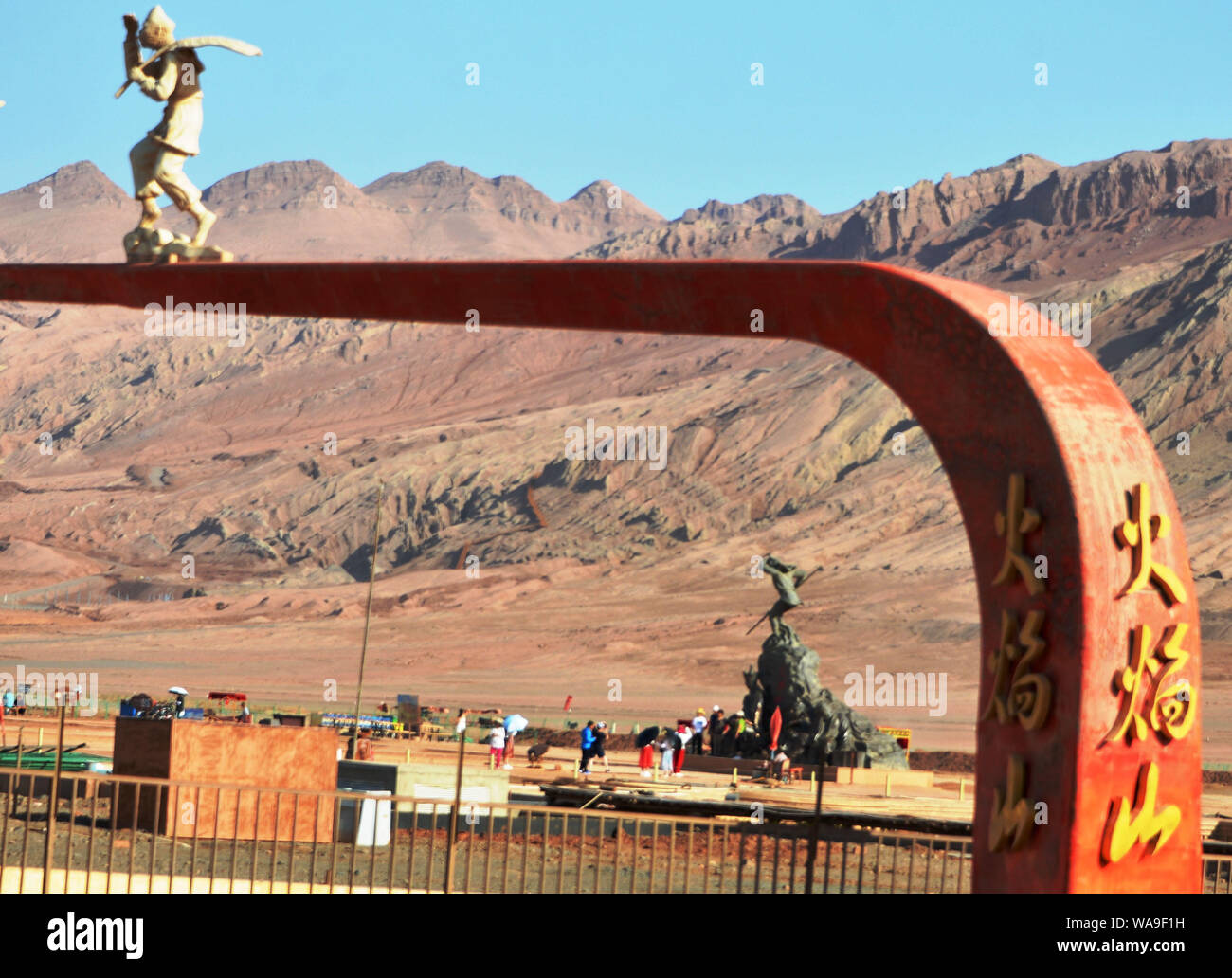 Tourists pose for photos with the landmark sculpture at the foot of the ...