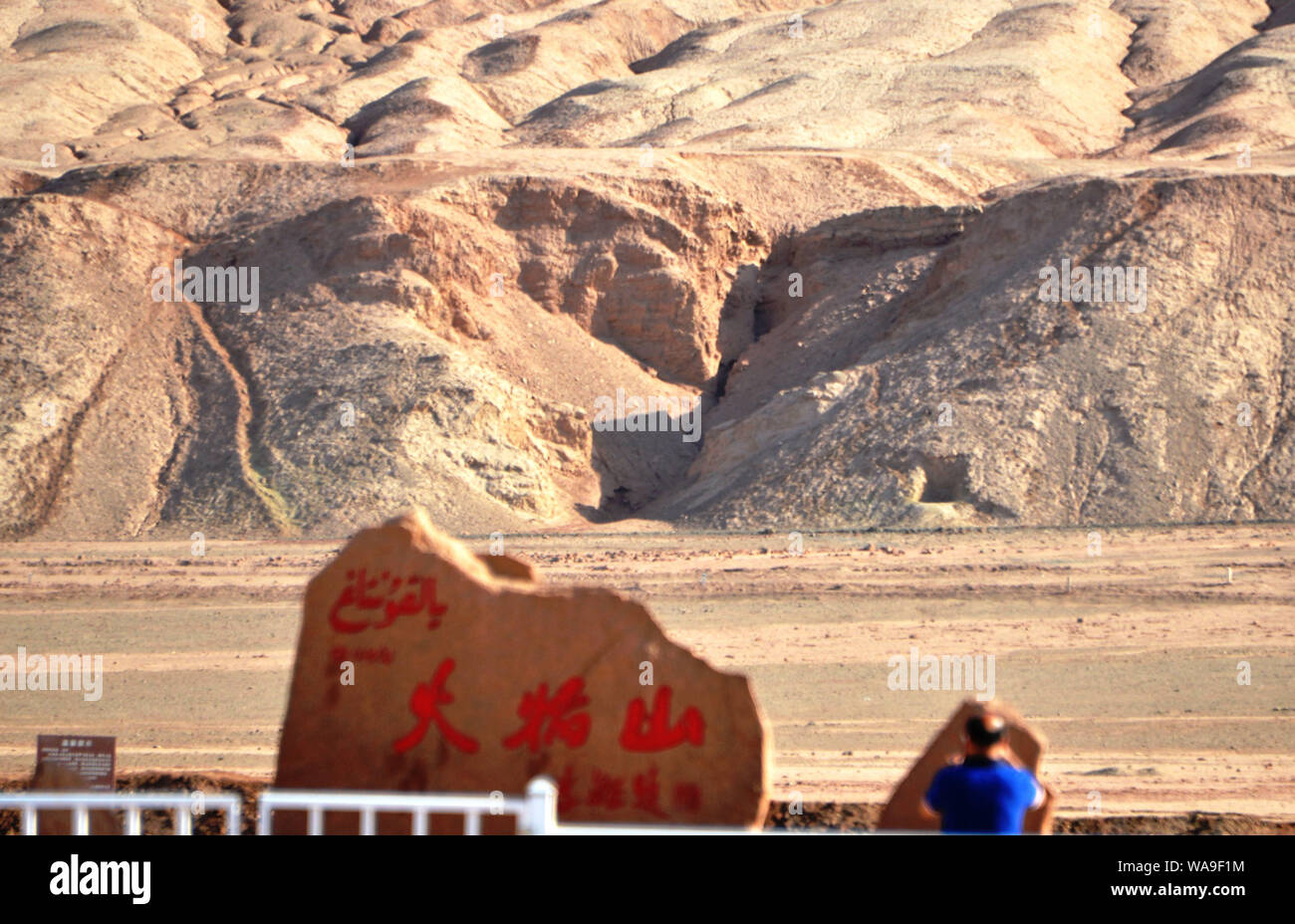 Tourists pose for photos with the landmark sculpture at the foot of the ...