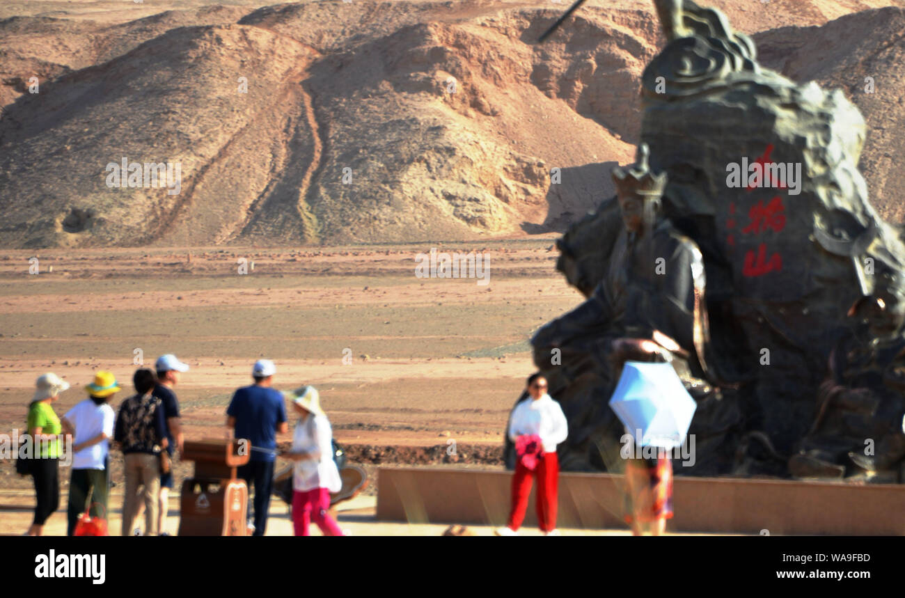 Tourists pose for photos with the landmark sculpture at the foot of the ...