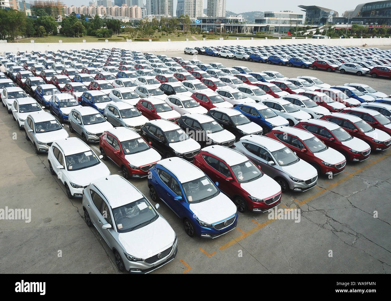 Cars waiting to be exported aboard are lined up at a port in ...
