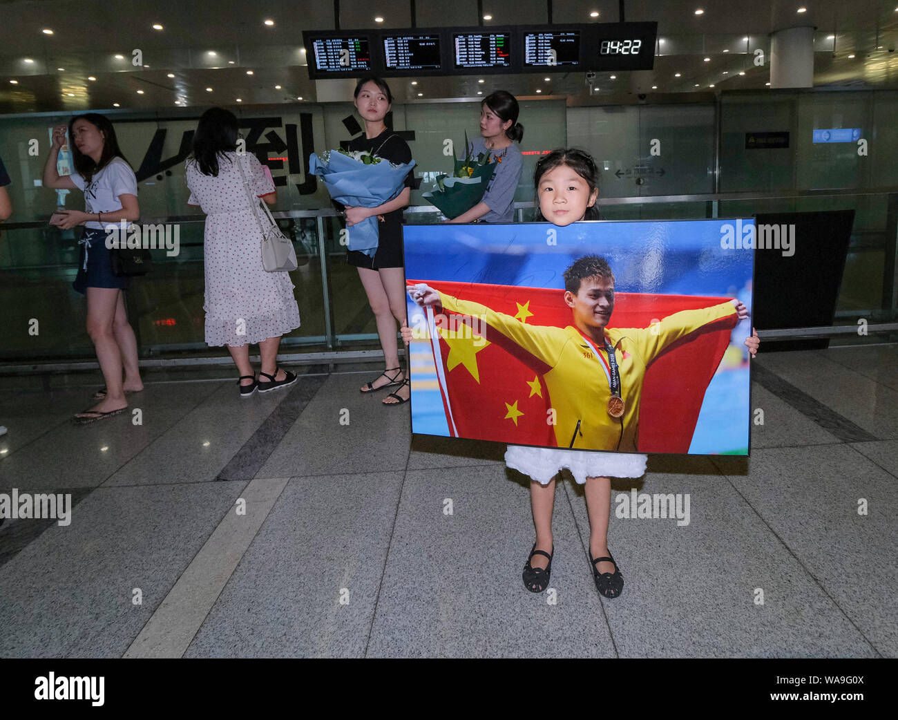 A little Chinese fan holds a picture of Chinese swimming Olympic ...