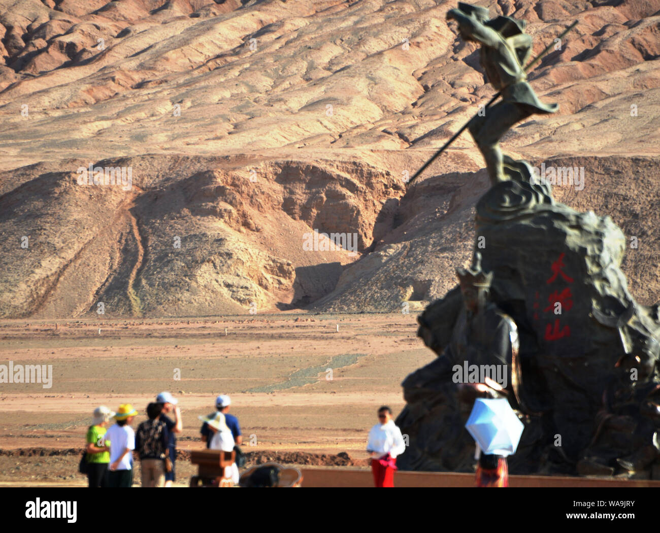 Tourists pose for photos with the landmark sculpture at the foot of the ...