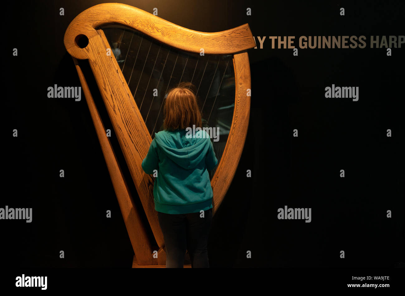 Young tourist girl playing on a Guinness Irish harp replica in the ...