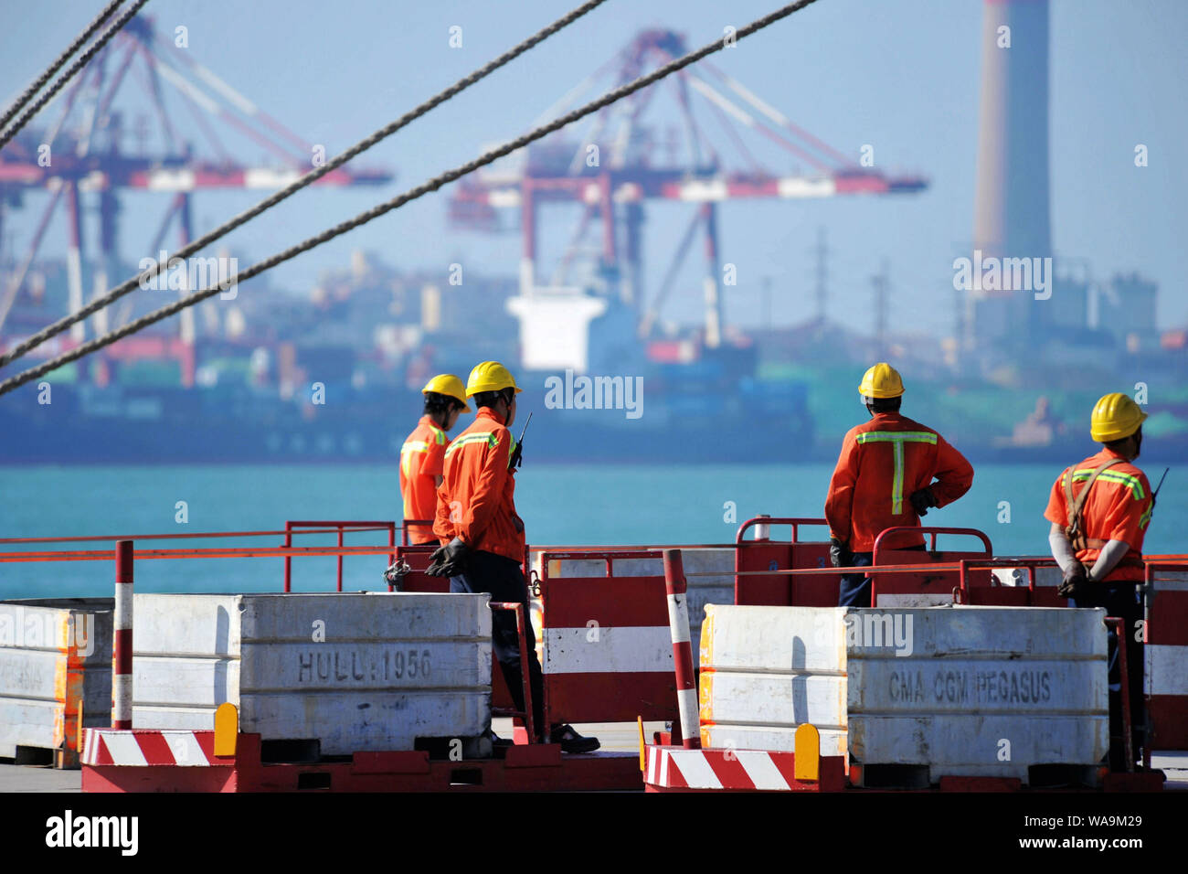 --FILE--Chinese workers look at cargo ships loaded with containers to ...