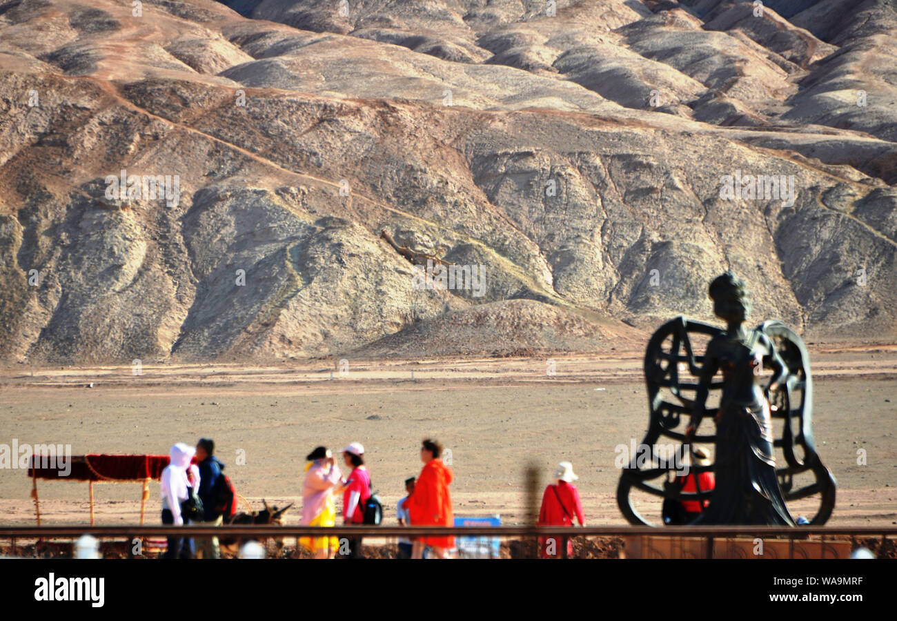 Tourists pose for photos with the landmark sculpture at the foot of the ...