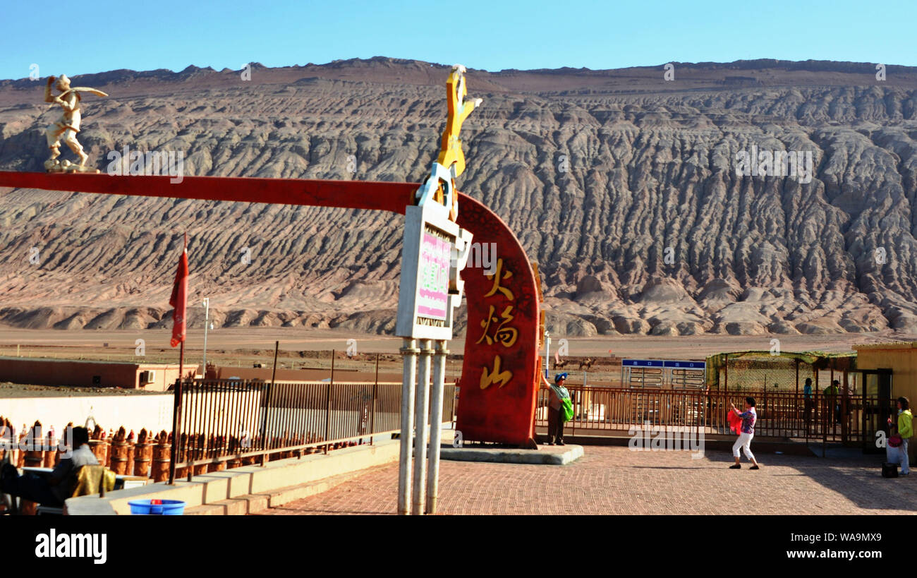 Tourists pose for photos with the landmark sculpture at the foot of the ...