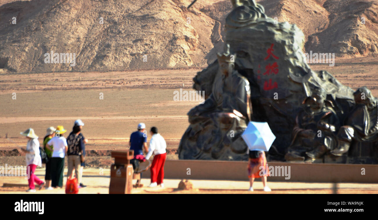 Tourists pose for photos with the landmark sculpture at the foot of the ...