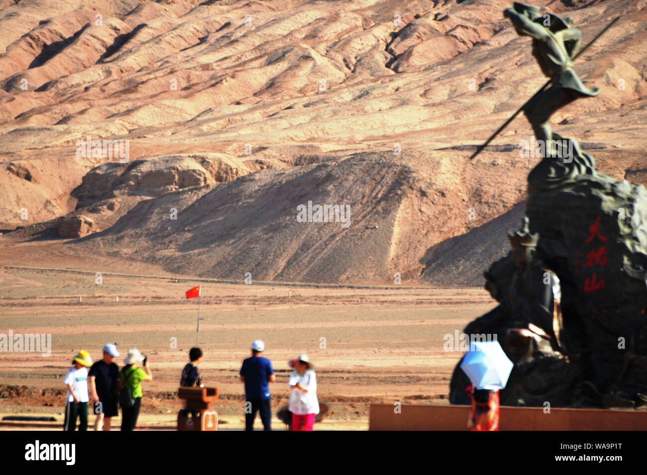 Tourists pose for photos with the landmark sculpture at the foot of the ...