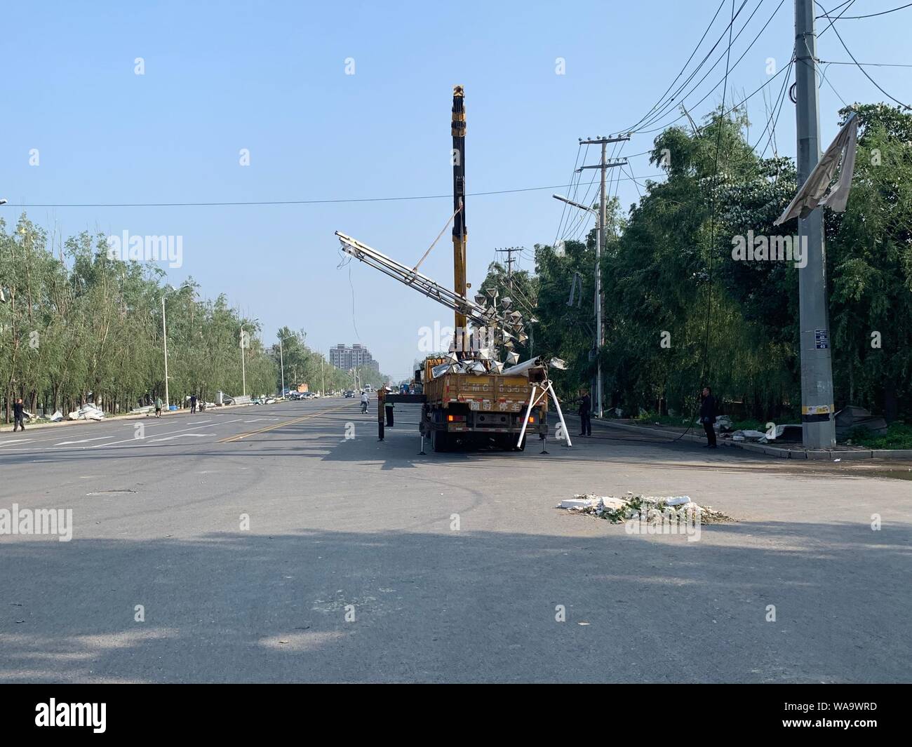 Chinese workers clear away the debris of trees and telegraph poles ...