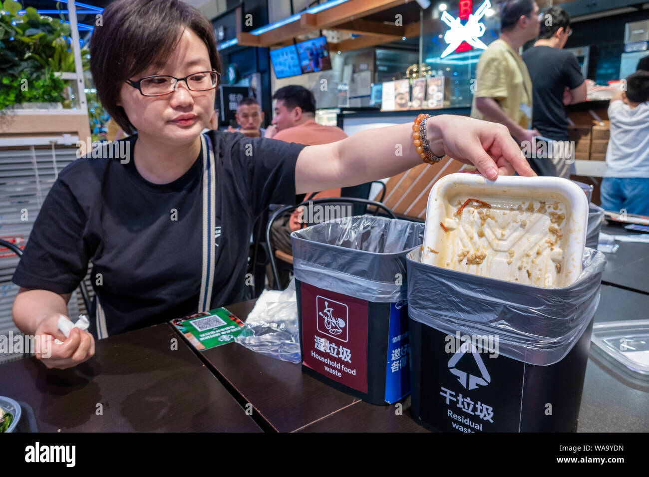 A customer puts waste of crayfish into a bin at a store of O2O fresh ...