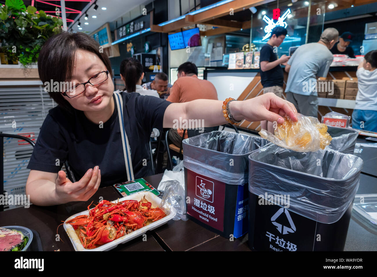 A customer puts waste of crayfish into a bin at a store of O2O fresh ...