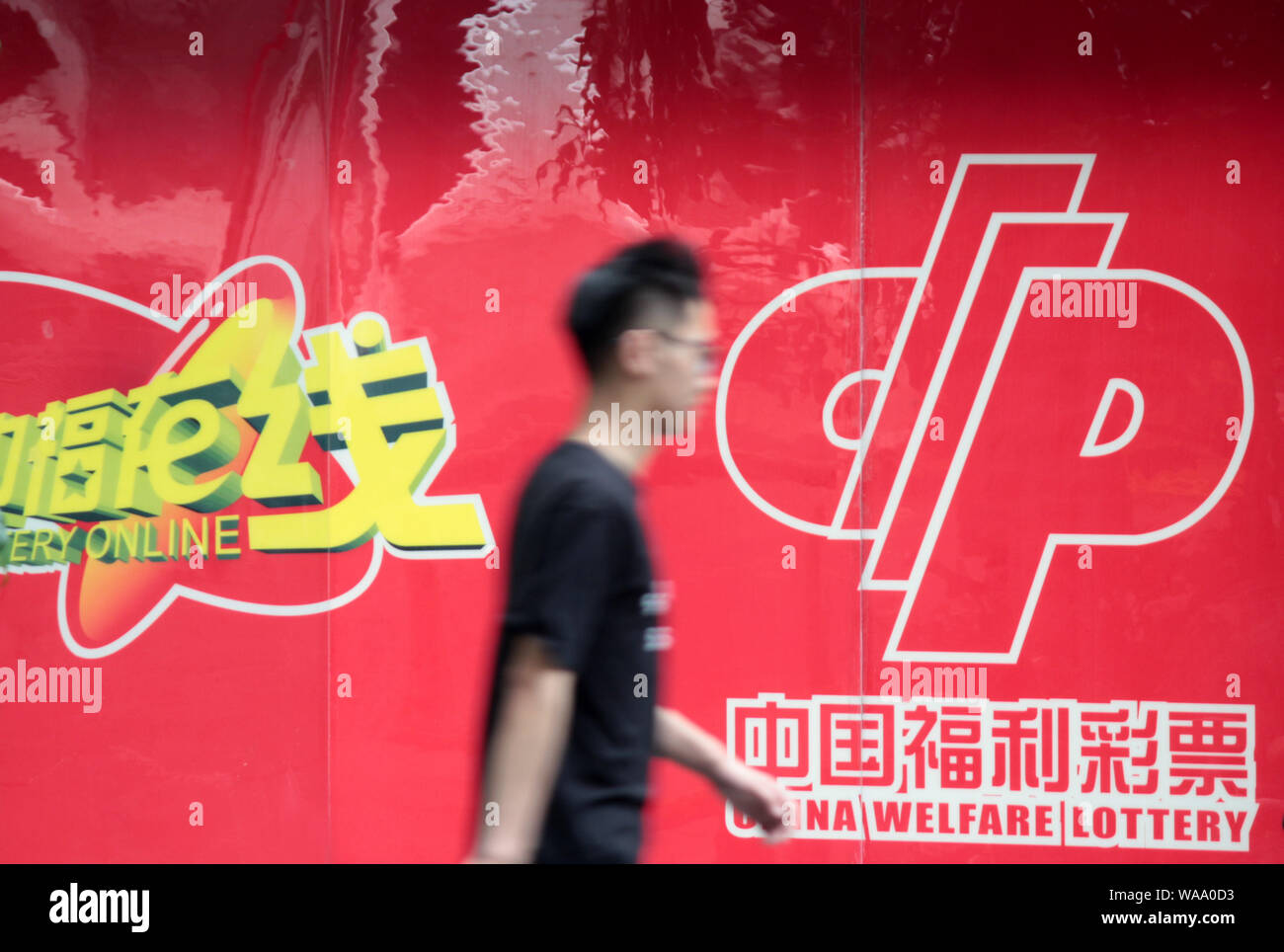 --FILE--A pedestrian walks past an advertisement for China Welfare ...