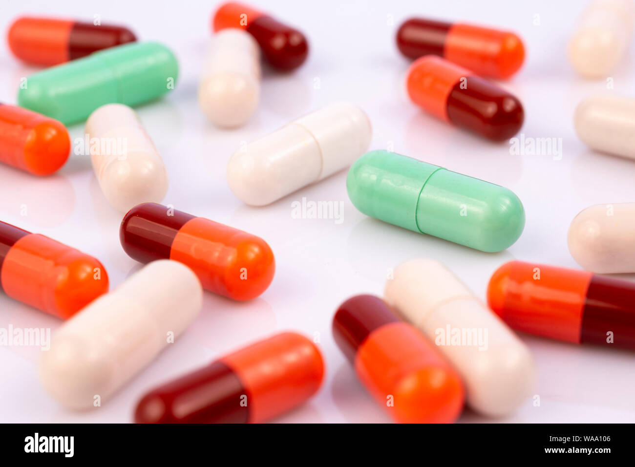 Colorful capsules and pills isolated on white reflective background ...