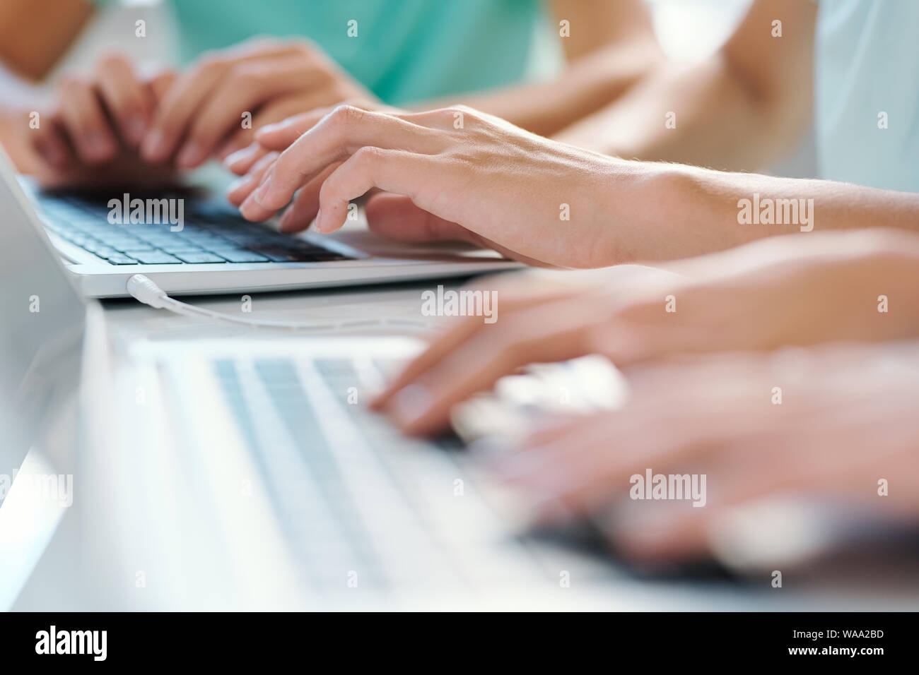 Hands of young students or schoolkids touching keys of laptop keypad ...