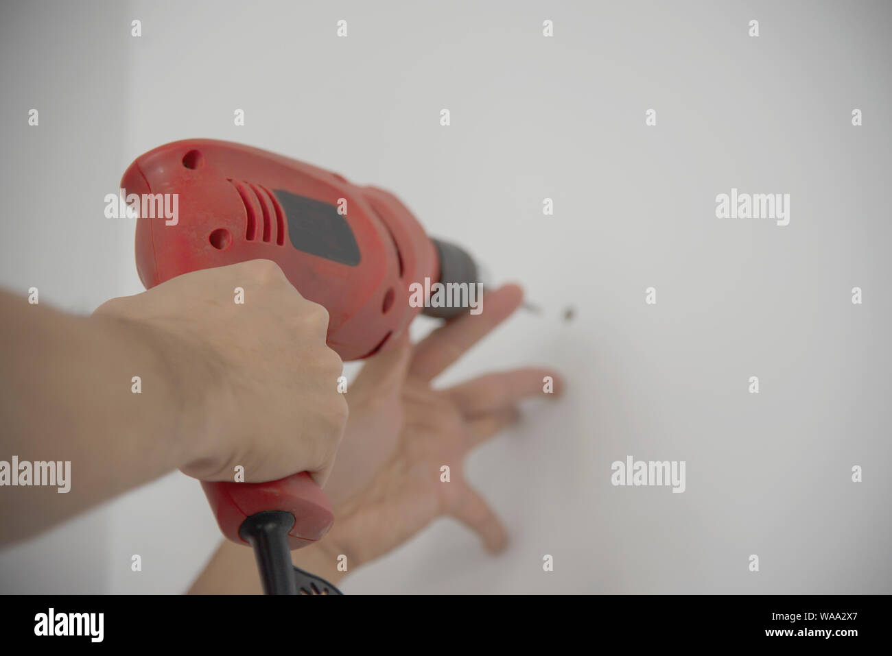 Man using hand drill device for installing home furniture at new white ...