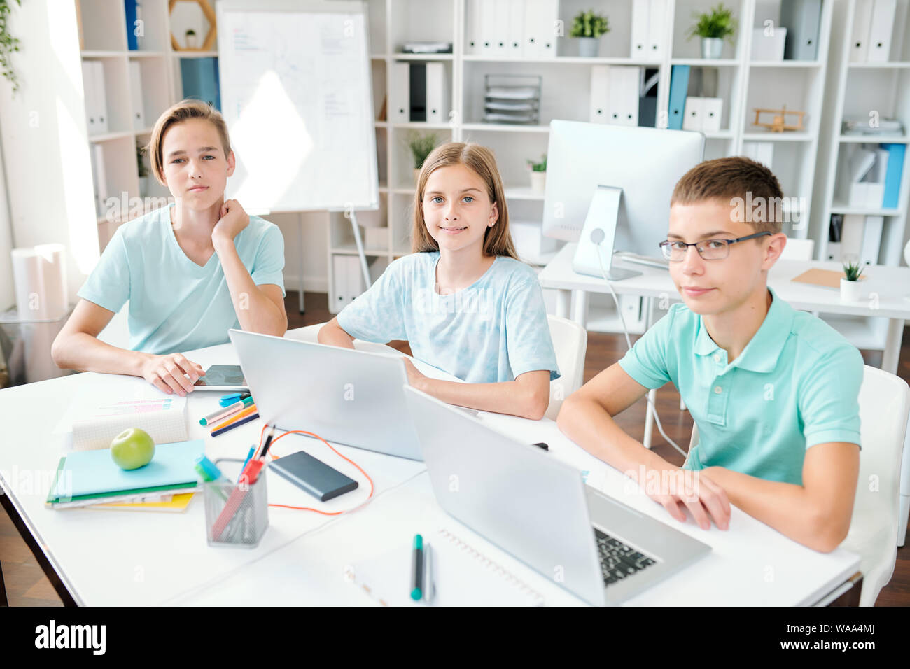 Three diligent learners of middle school doing homework in classroom ...