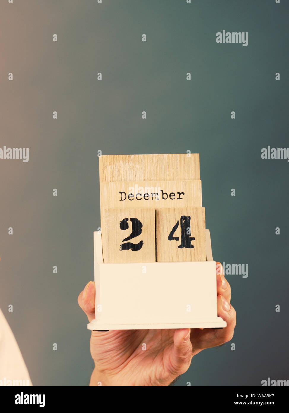 Man holding calendar with 24 december date in hands, on dark blue ...