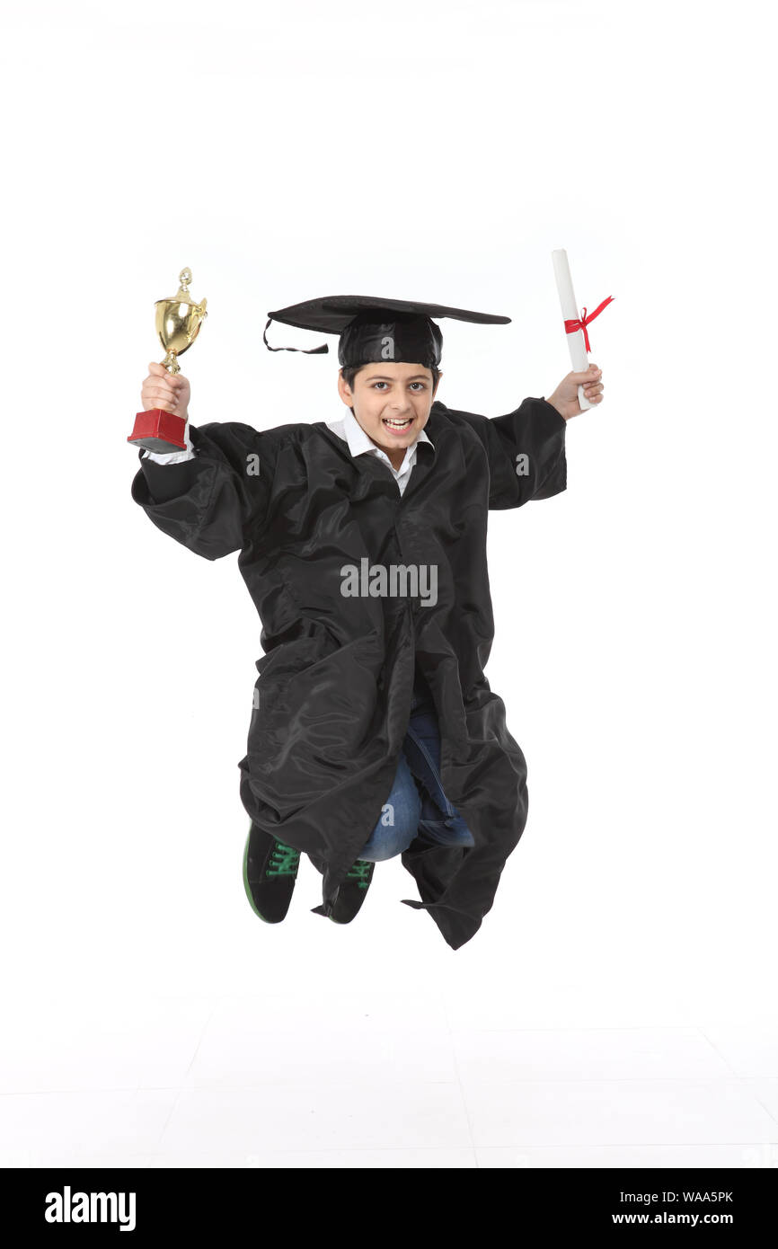 Boy in graduation gown showing a degree with trophy Stock Photo - Alamy