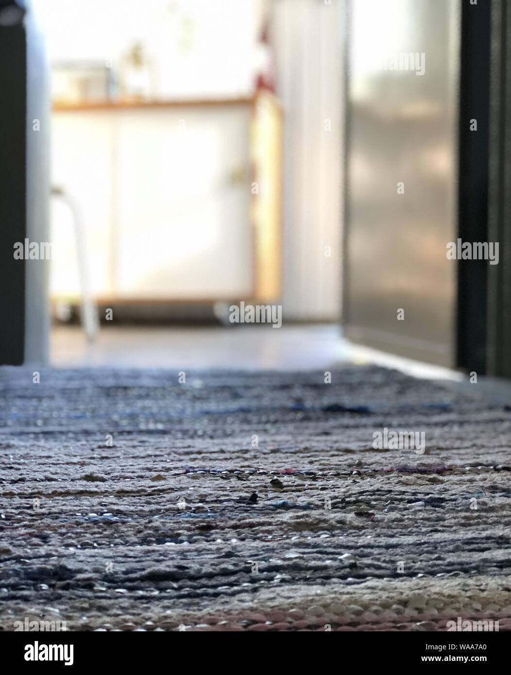 Vertical selective focus closeup shot of a carpet near a kitchen door ...
