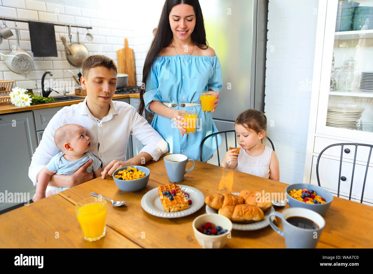 Family of four having breakfast In the kitchen Stock Photo - Alamy