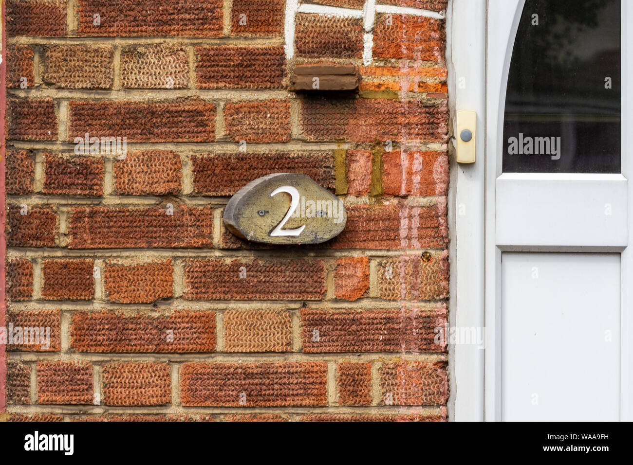 House number two on a red brick wall with the 2 carved in wood Stock ...