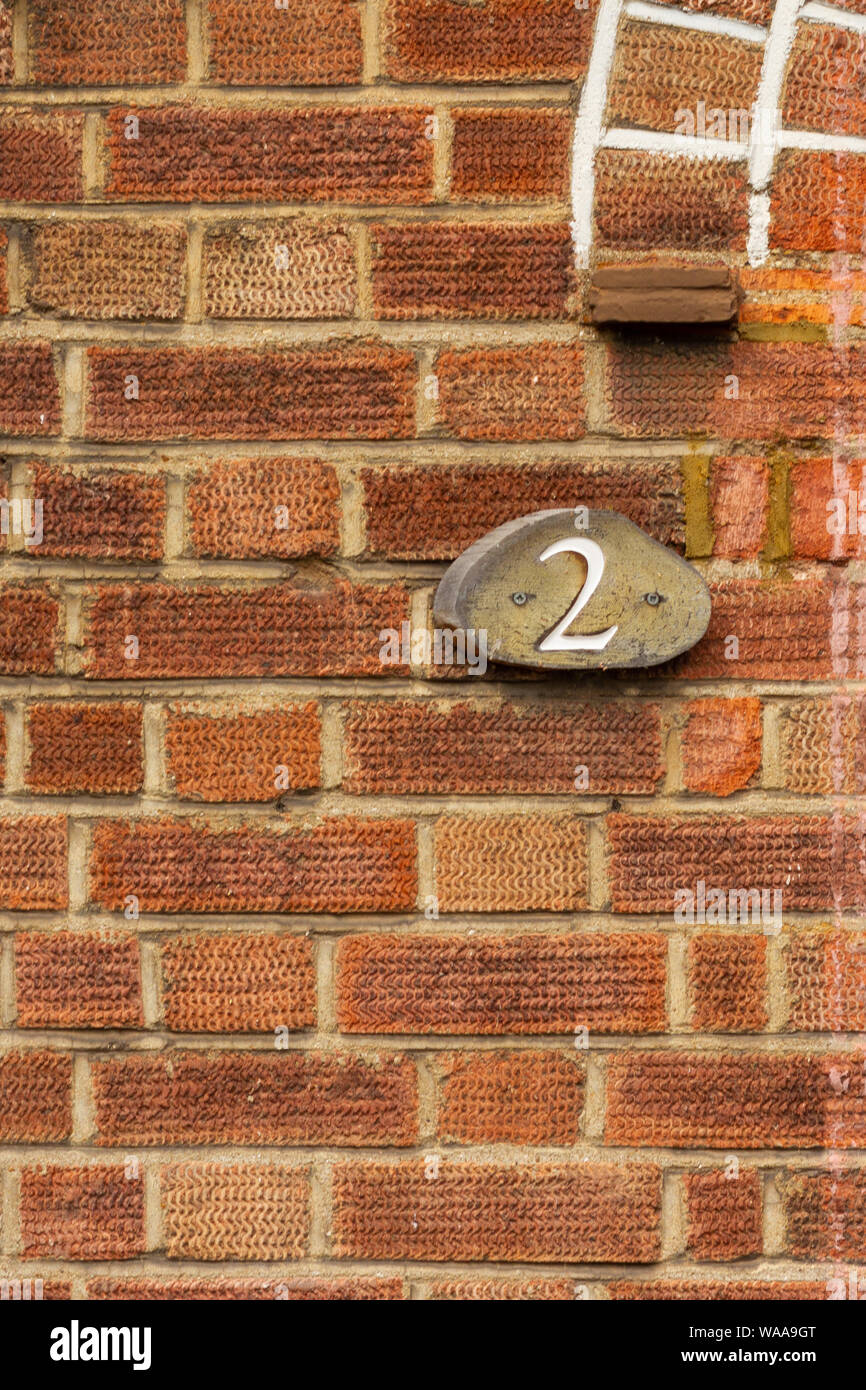 House number two on a red brick wall with the 2 carved in wood Stock ...