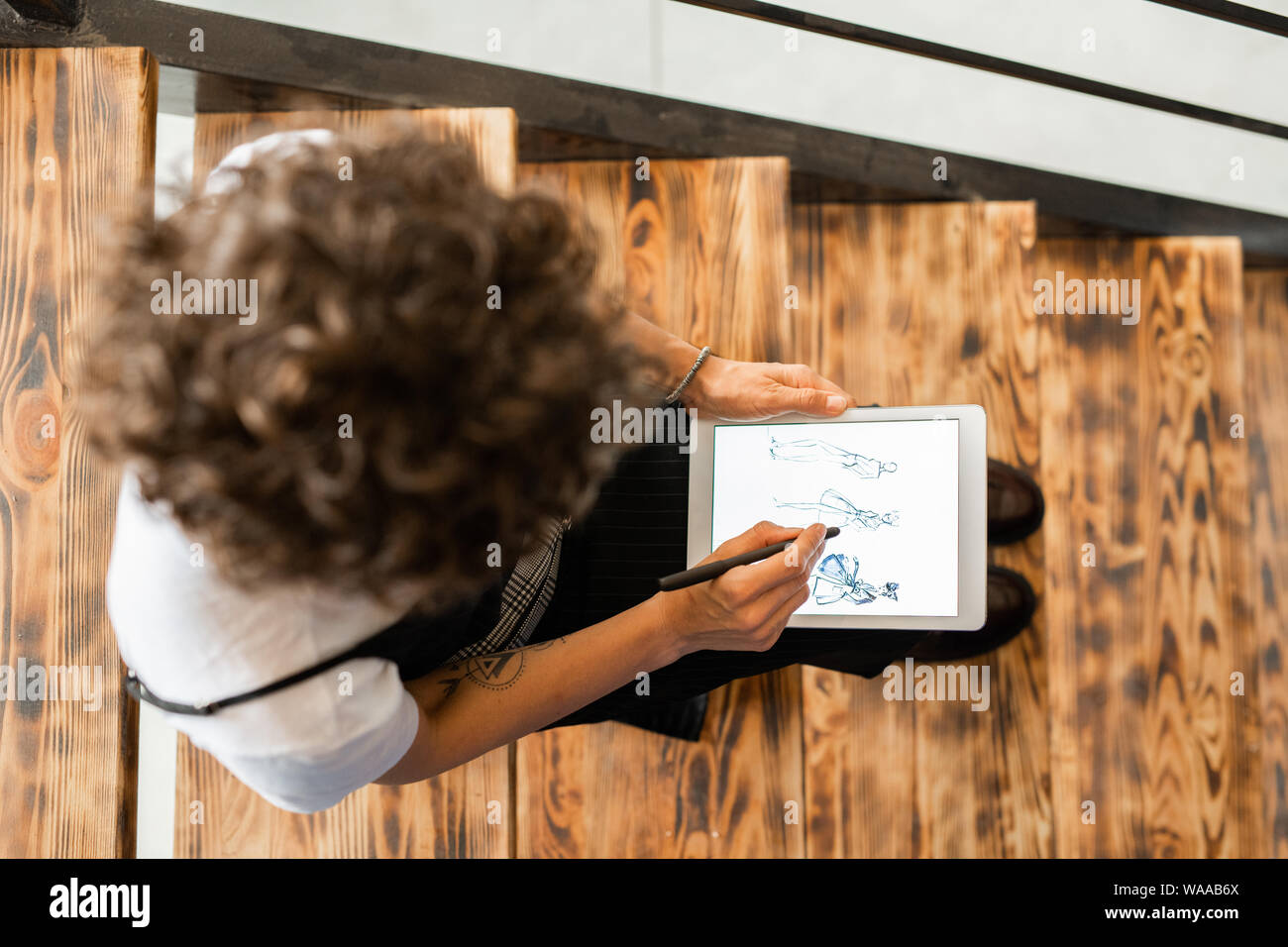 Top view of young female fashion designer making sketches of new models ...