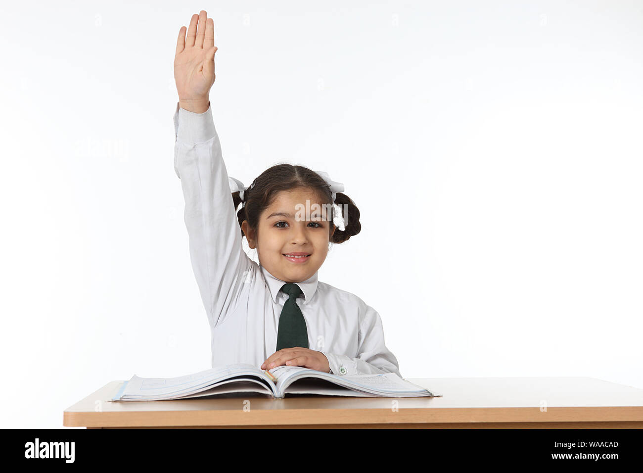 Schoolgirl raising hand in classroom Stock Photo - Alamy