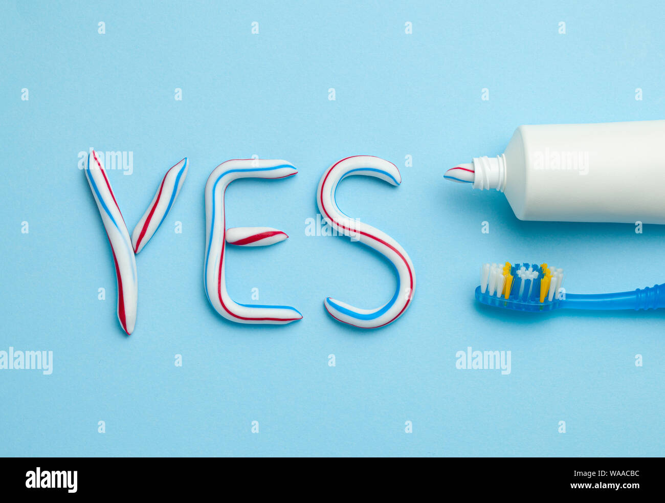 Word YES from toothpaste. Tube of colored toothpaste and toothbrush on ...
