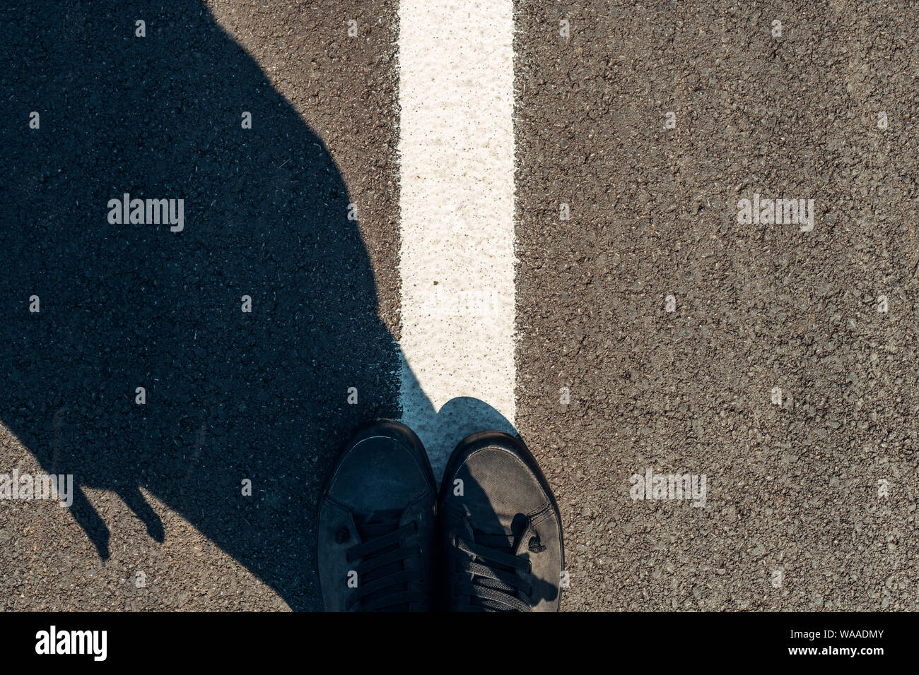 Urban explorer, man in modern shoes standing on asphalt road with white ...