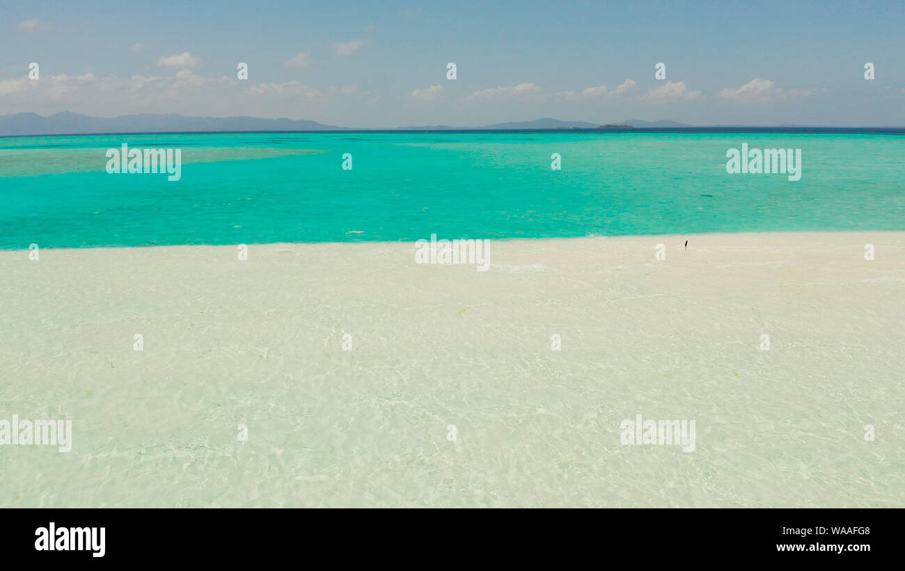 Tropical coral atoll with turquoise water against the sky with clouds ...