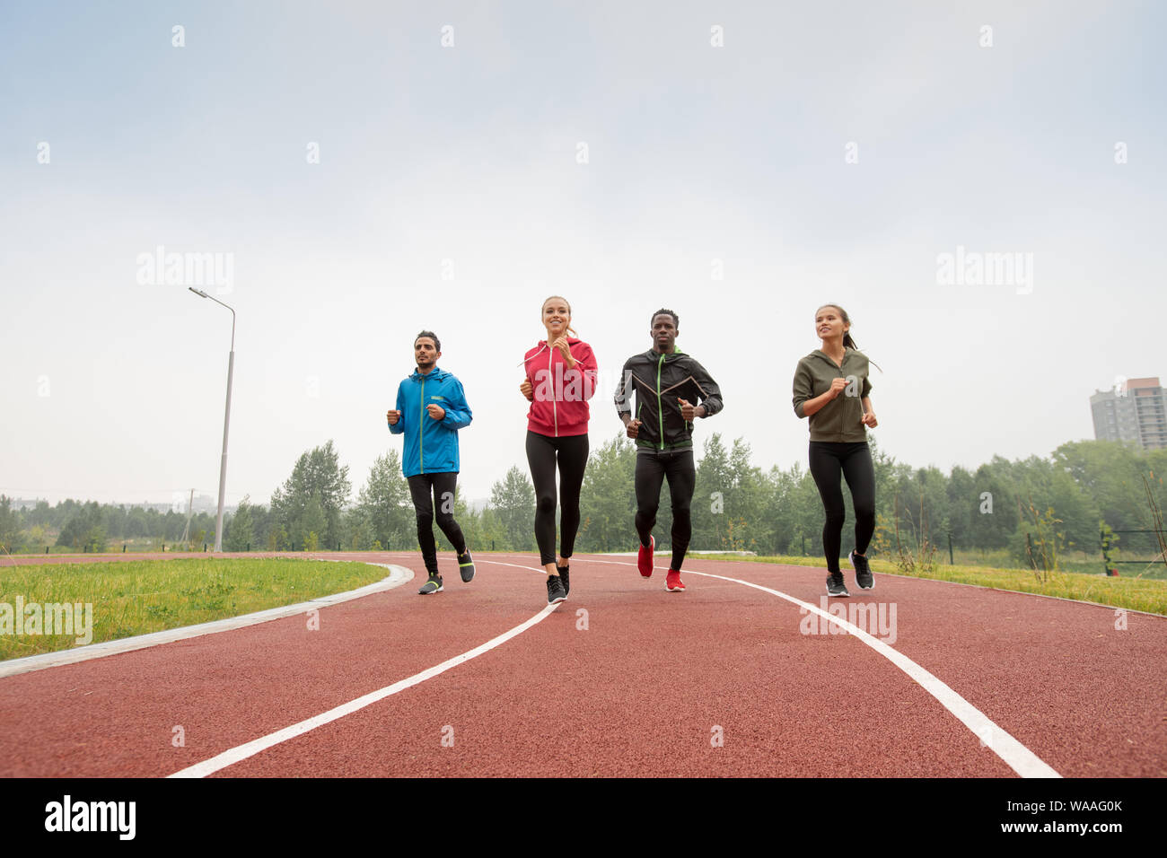 Four young male and female athletes in sportswear running marathon ...