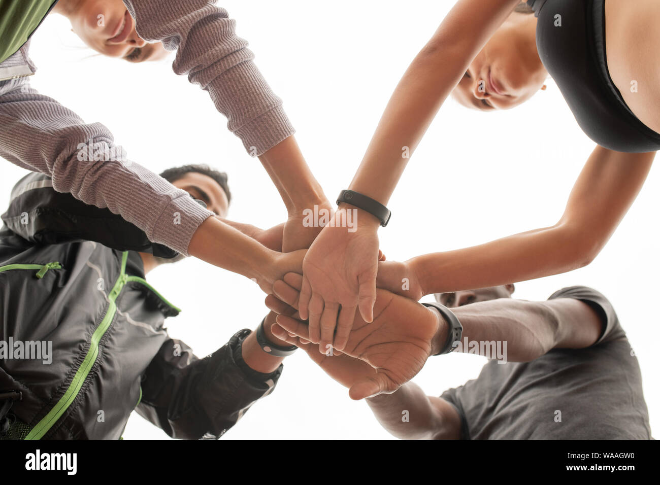 Below angle of young intercultural sporty people maing pile of hands ...