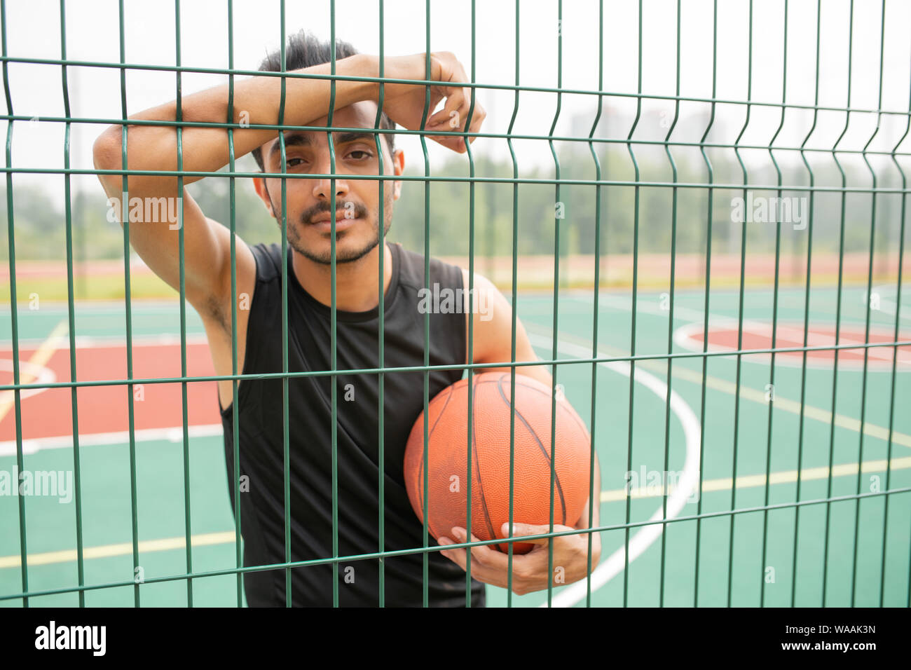 Serious male basketball player with ball standing against net Stock ...