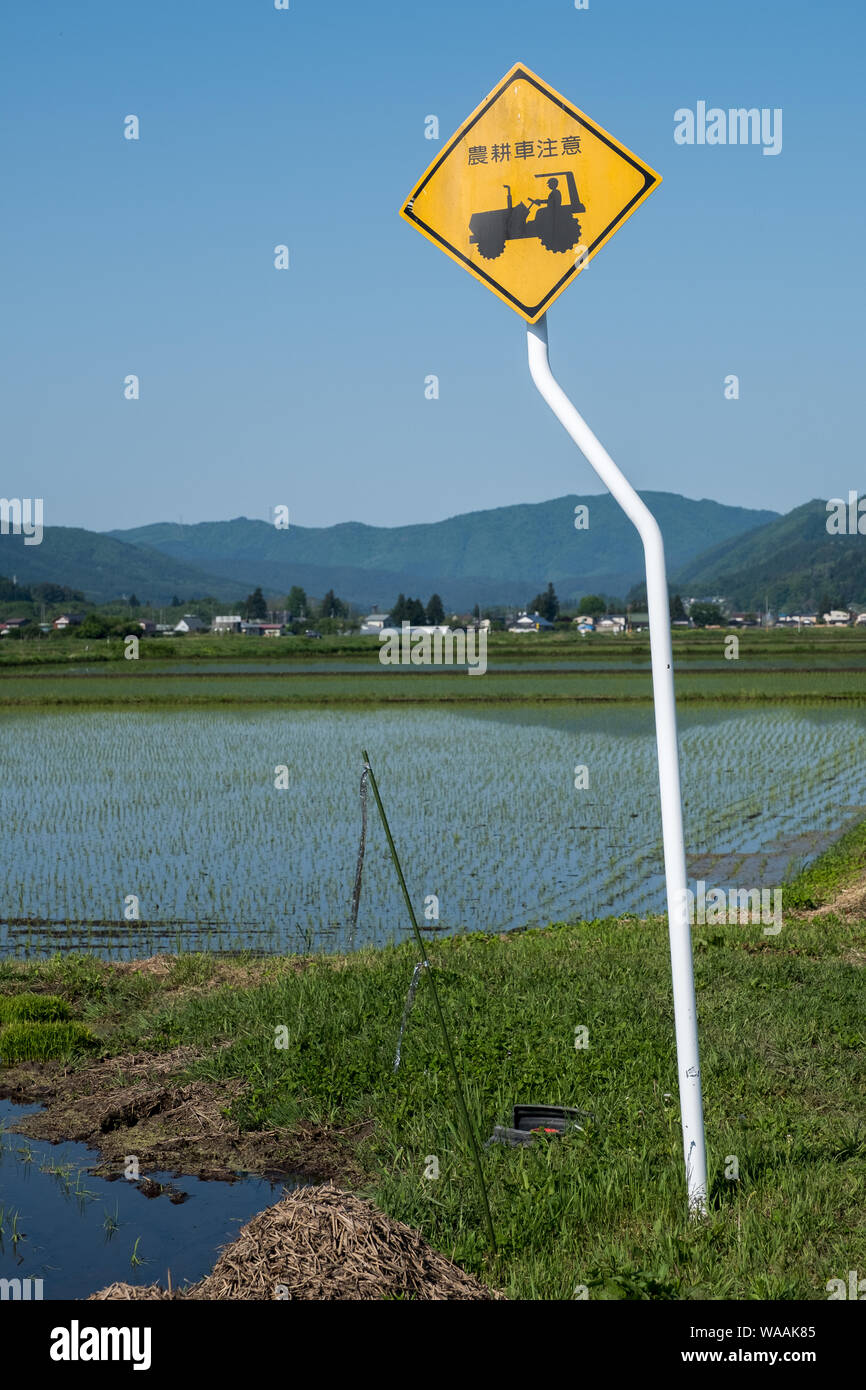 A yellow tractor sign in front of a rice field in rural Japan Stock ...