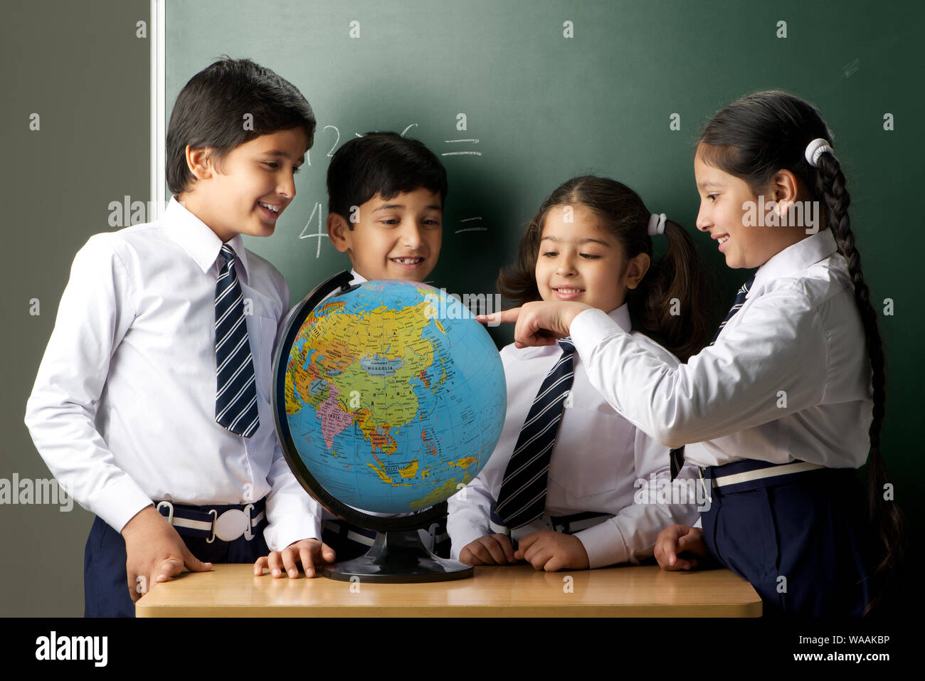 Students looking at globe in classroom Stock Photo - Alamy
