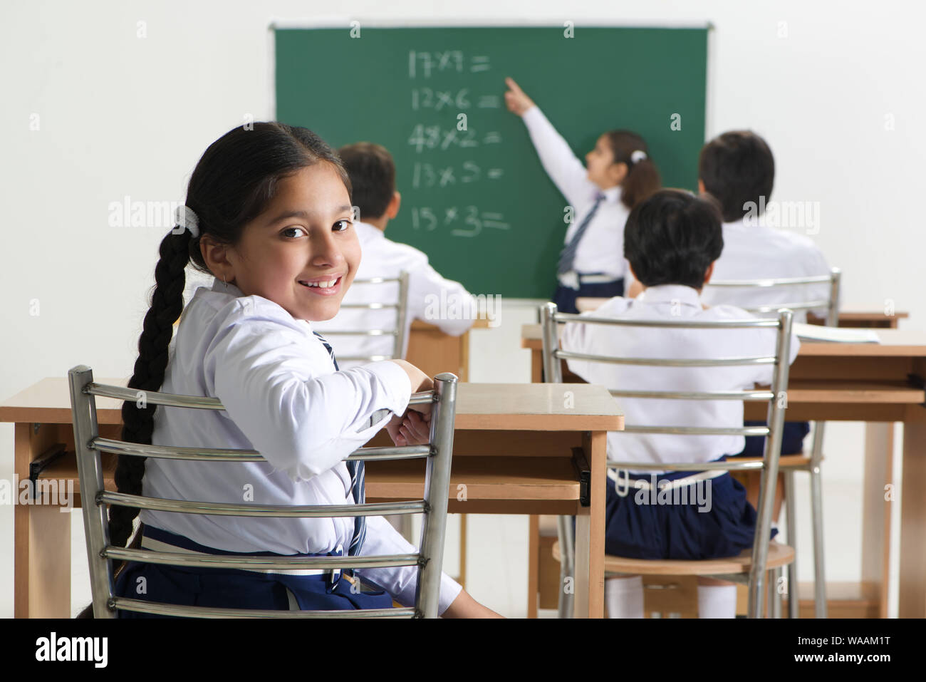 Schoolgirl looking back towards camera and schoolgirl teaching her ...