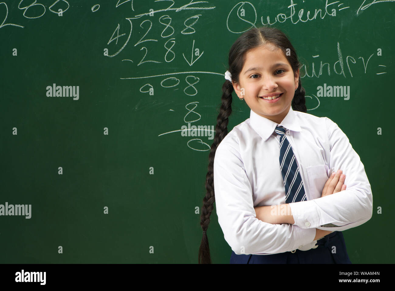 Schoolgirl standing with her arms crossed in a classroom Stock Photo ...