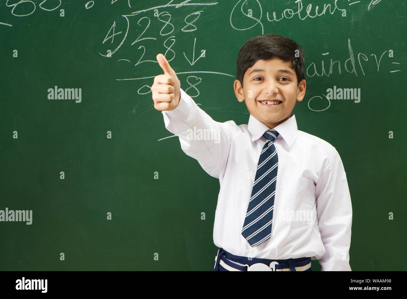 Schoolboy standing and showing thumbs up sign in a classroom Stock ...