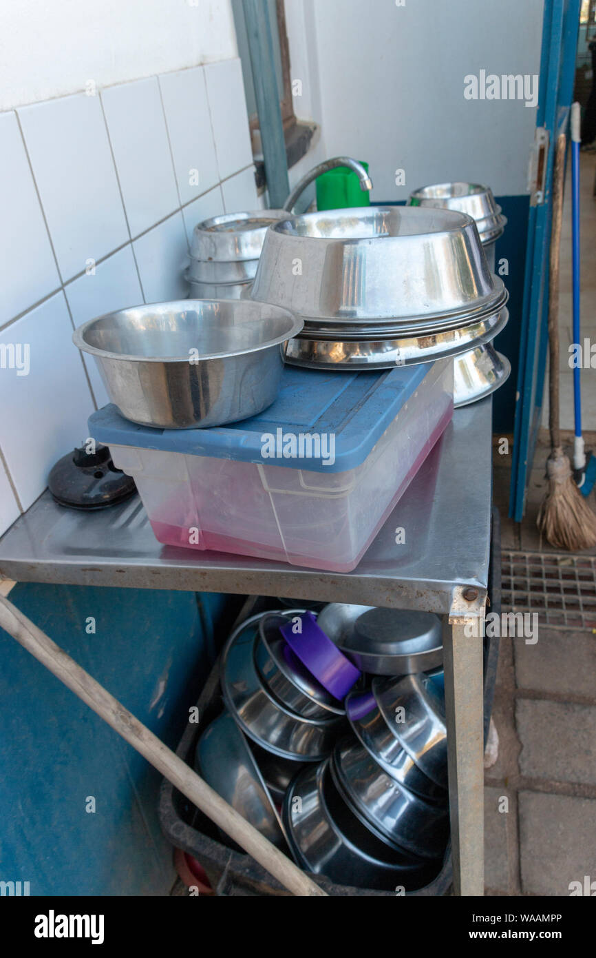 A close up view of metal dogs dishes piled up on a washing sink waiting ...
