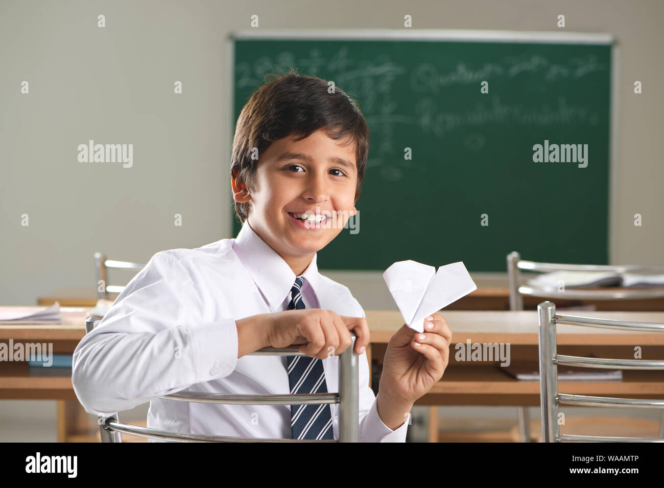 Schoolboy holding paper plane in classroom Stock Photo - Alamy