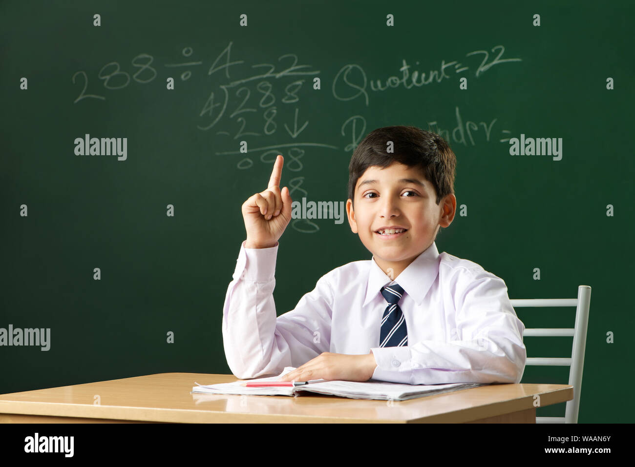 Schoolboy studying in a classroom and pointing upward Stock Photo - Alamy
