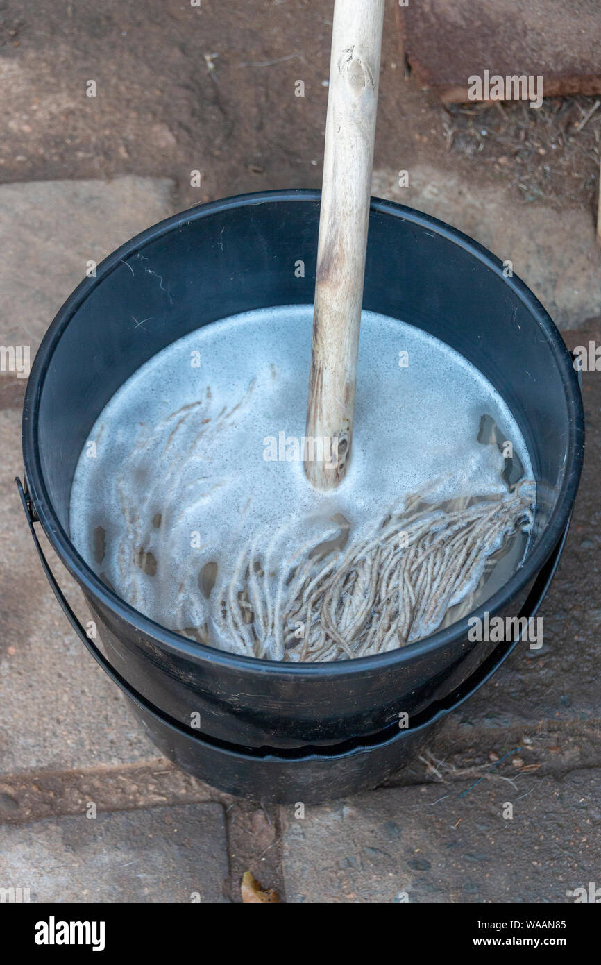 A close up view of a mop submerged in a plastic black bucket full of ...