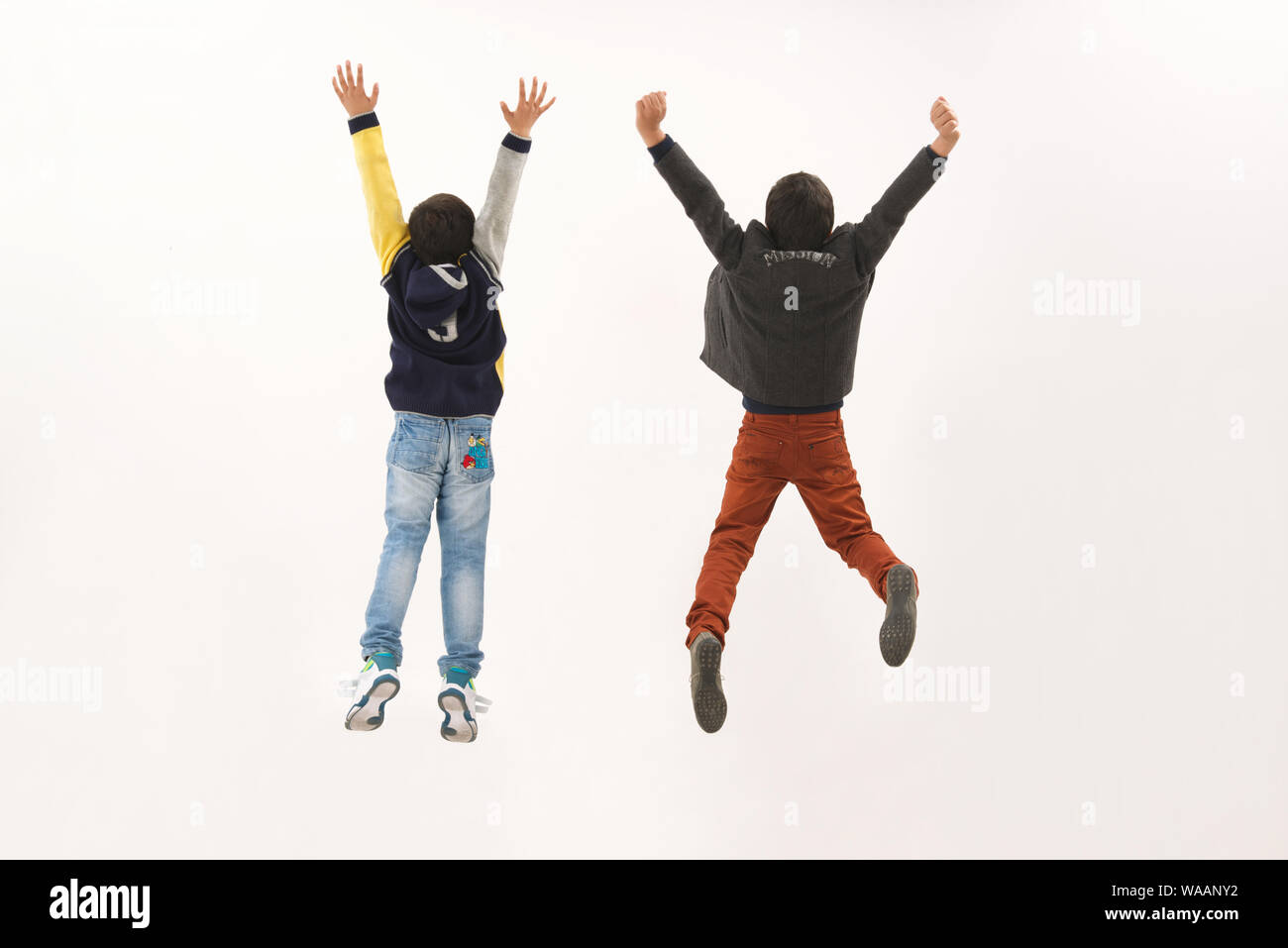 Rear view of two children jumping in air Stock Photo - Alamy