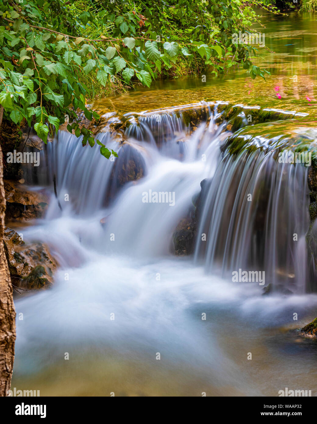 Small mountain waterfall on the rocks covered with moss in the forest ...