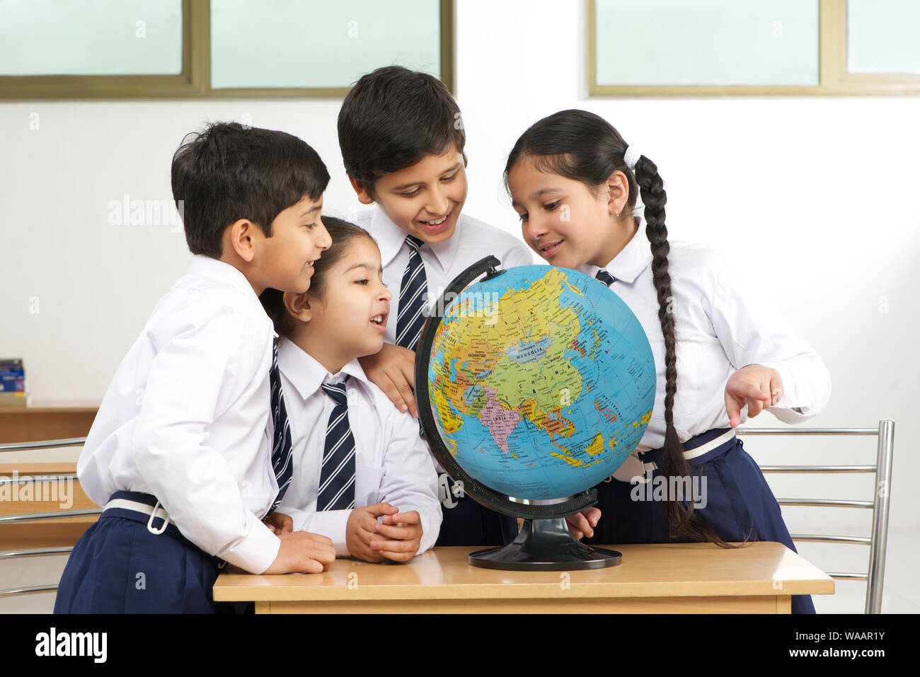 Students looking at globe in classroom Stock Photo - Alamy